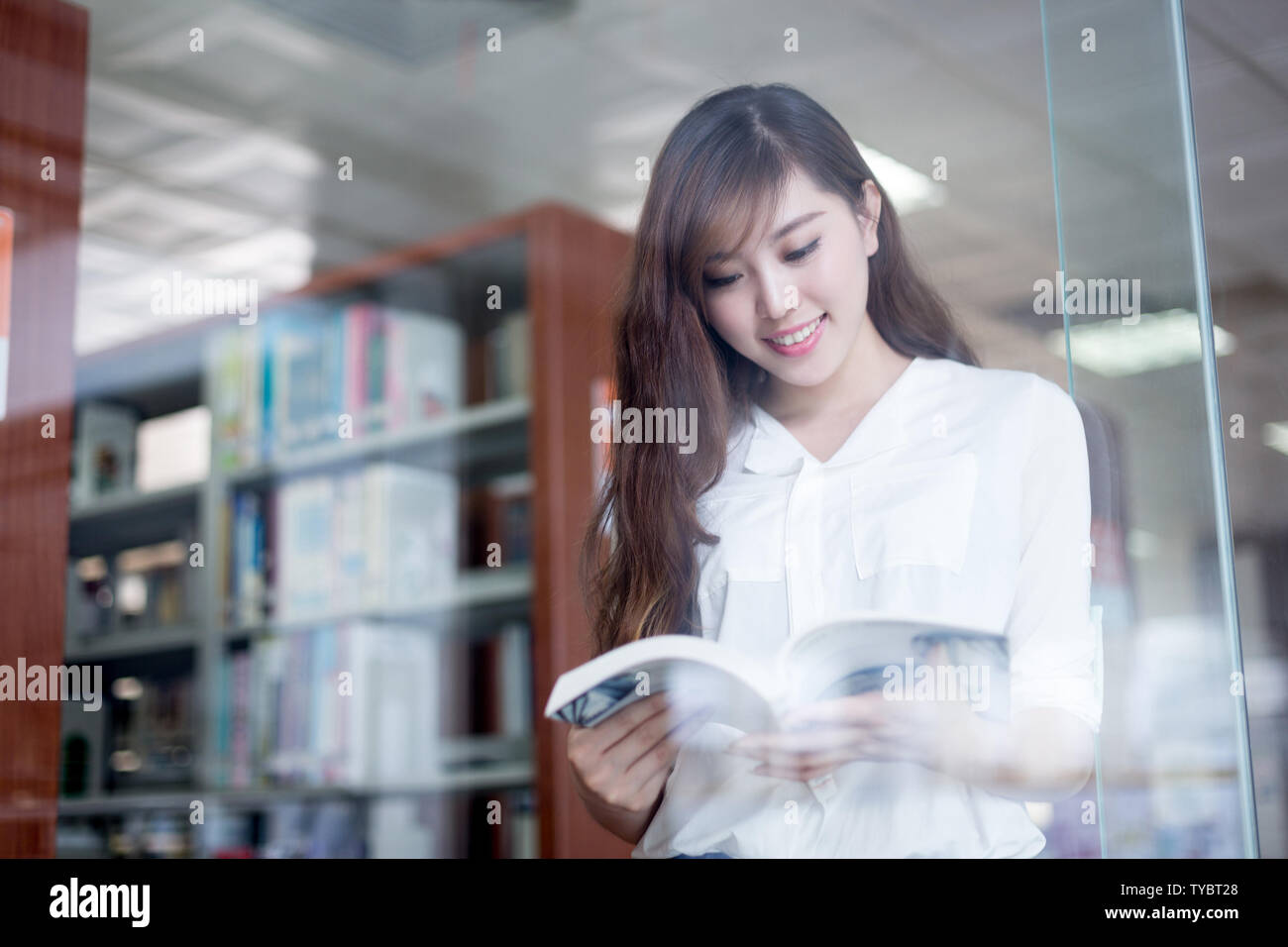 Asian beautiful female student holding book in library Stock Photo - Alamy