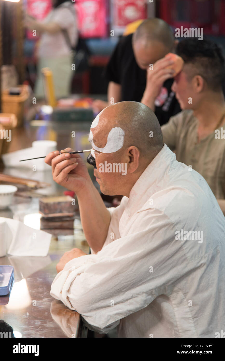 Traditional Chinese actor applies makeup before a performance in a ...