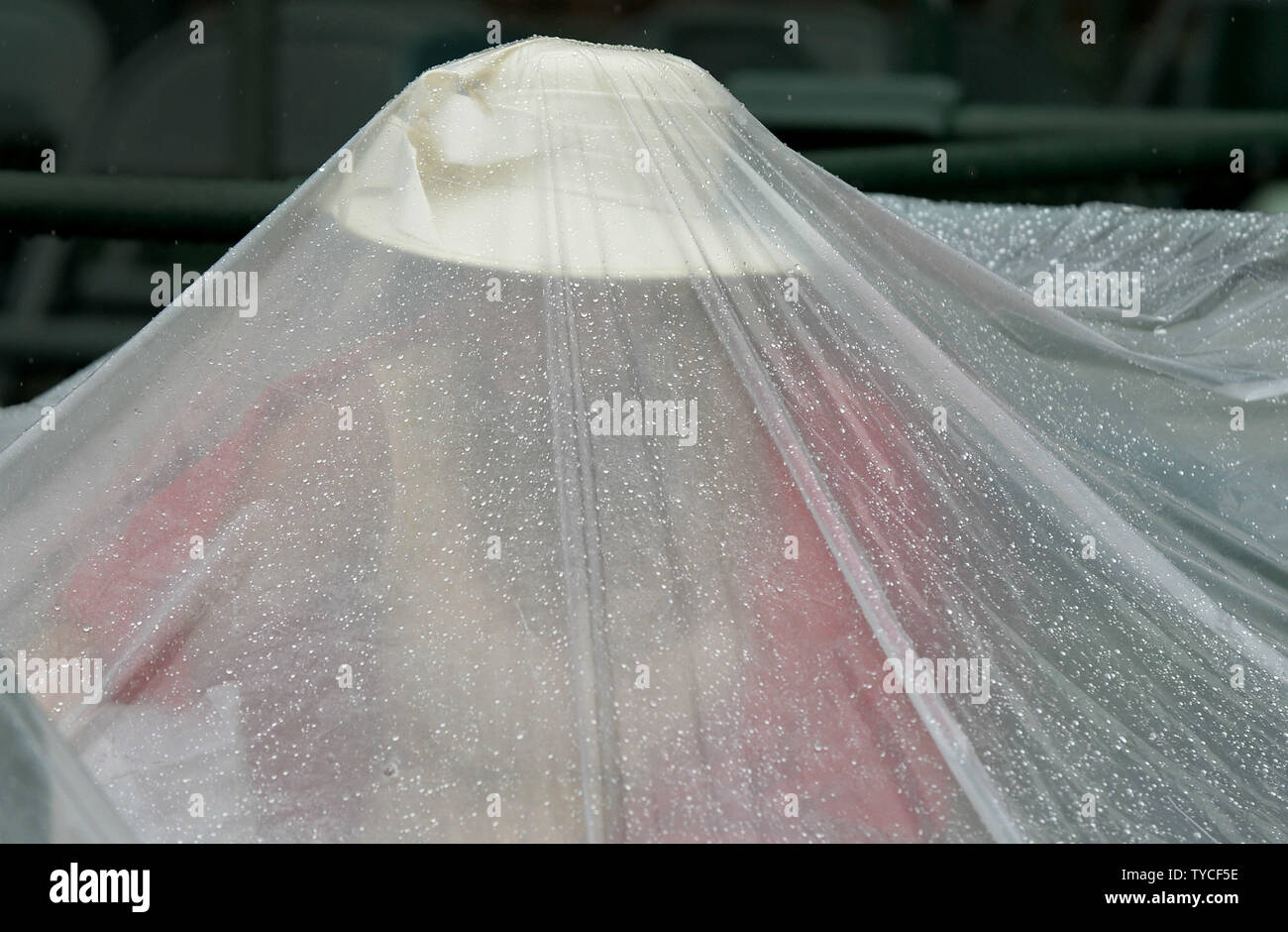 A race shields herself under a tarp as heavy rains fall prior to the ...