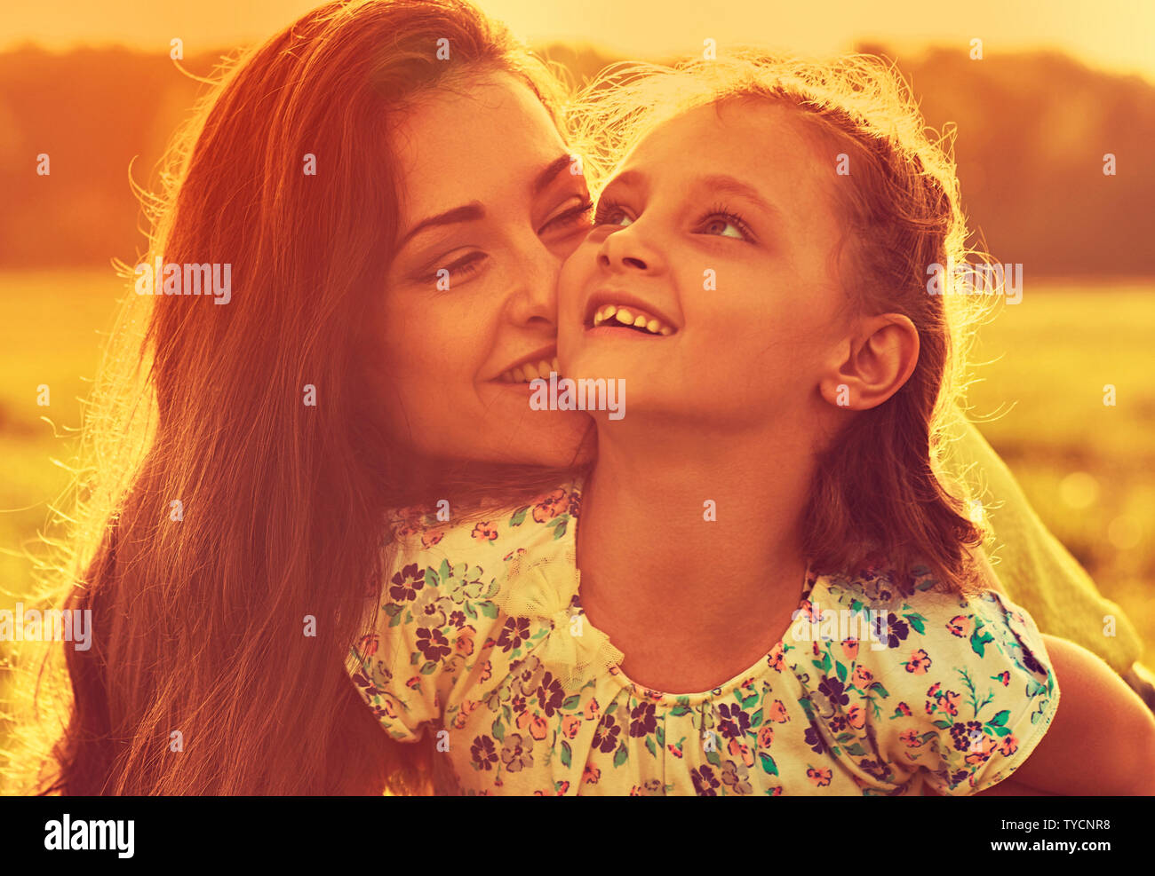 Happy enjoying mother hugging her playful laughing kid girl in sunset sunny light on summer ...