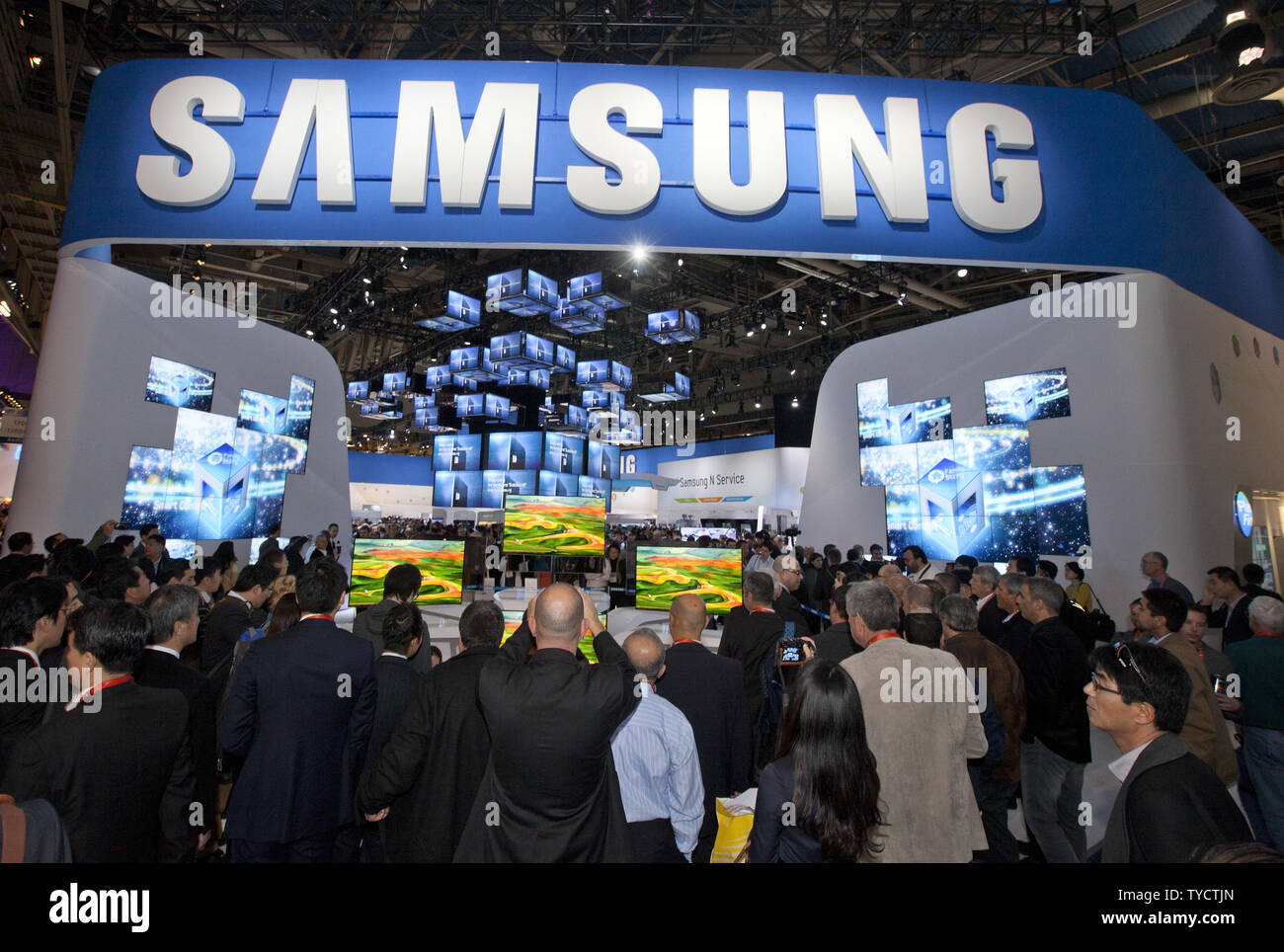 Visitors stand at the entrance to the Samsung exhibit watching video ...