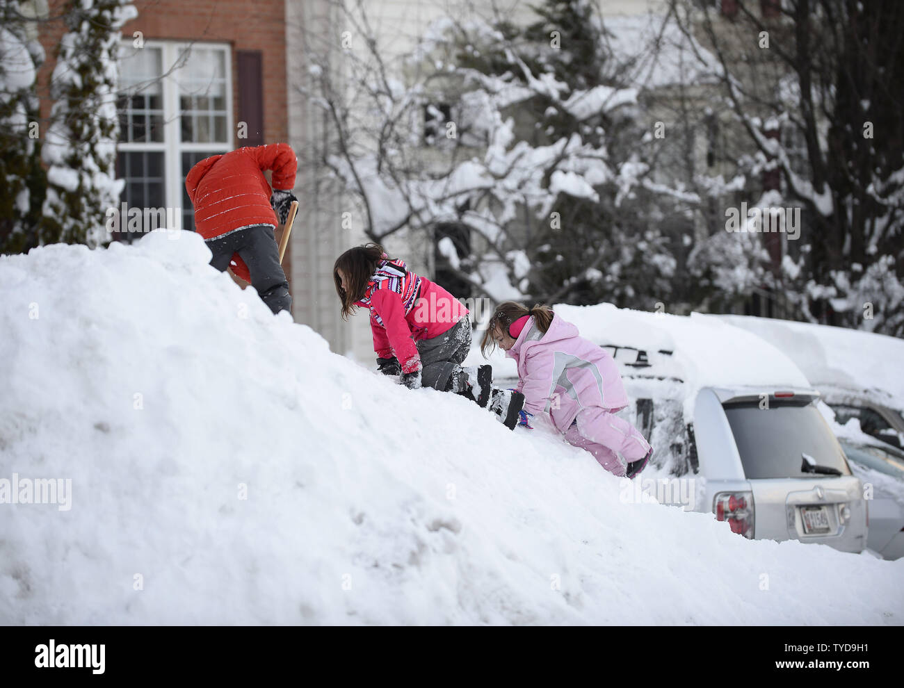 Children play atop a mound of snow taller than automobiles as residents ...