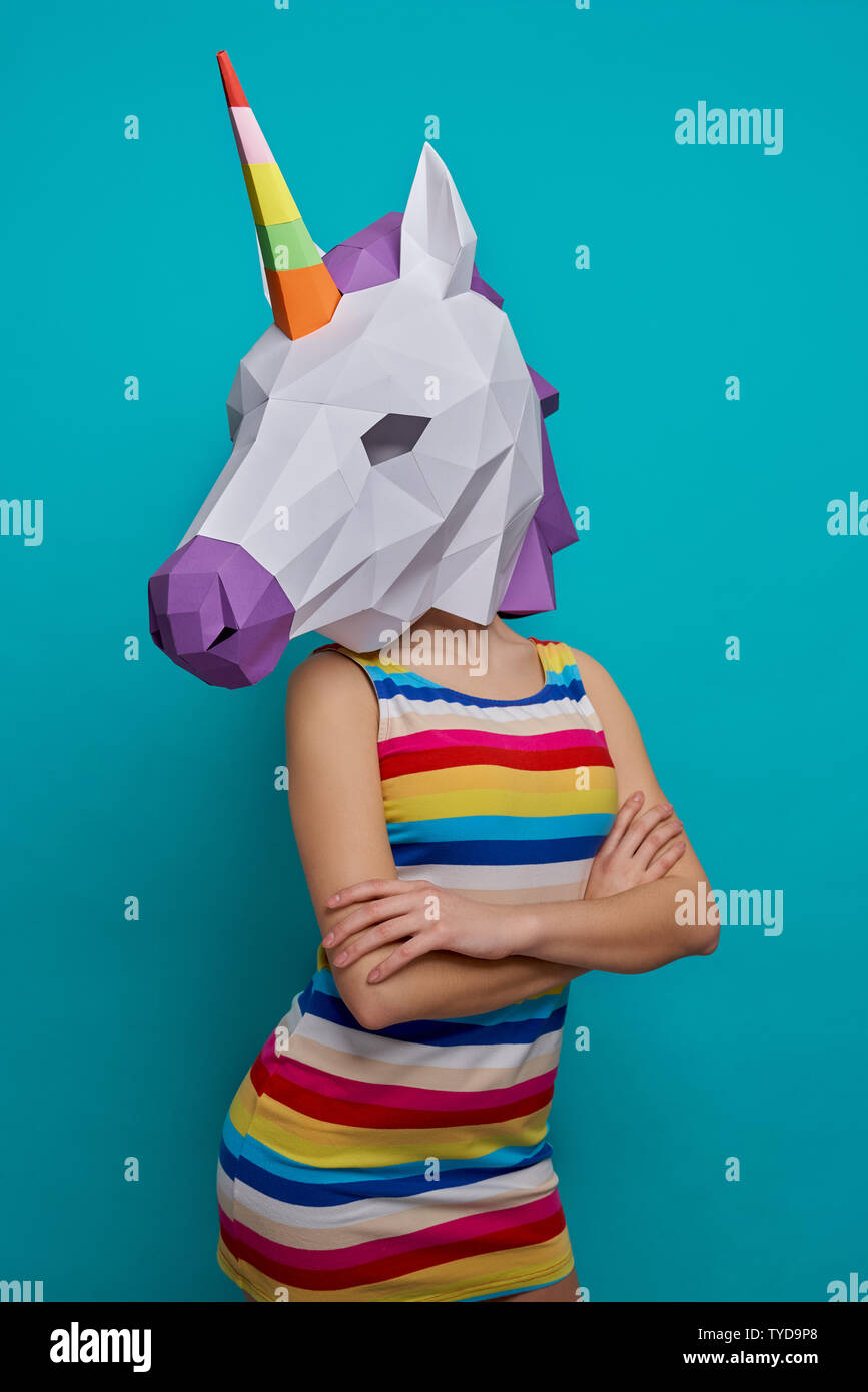 Slender, stylish model posing with paper 3D unicorn on head on blue ...