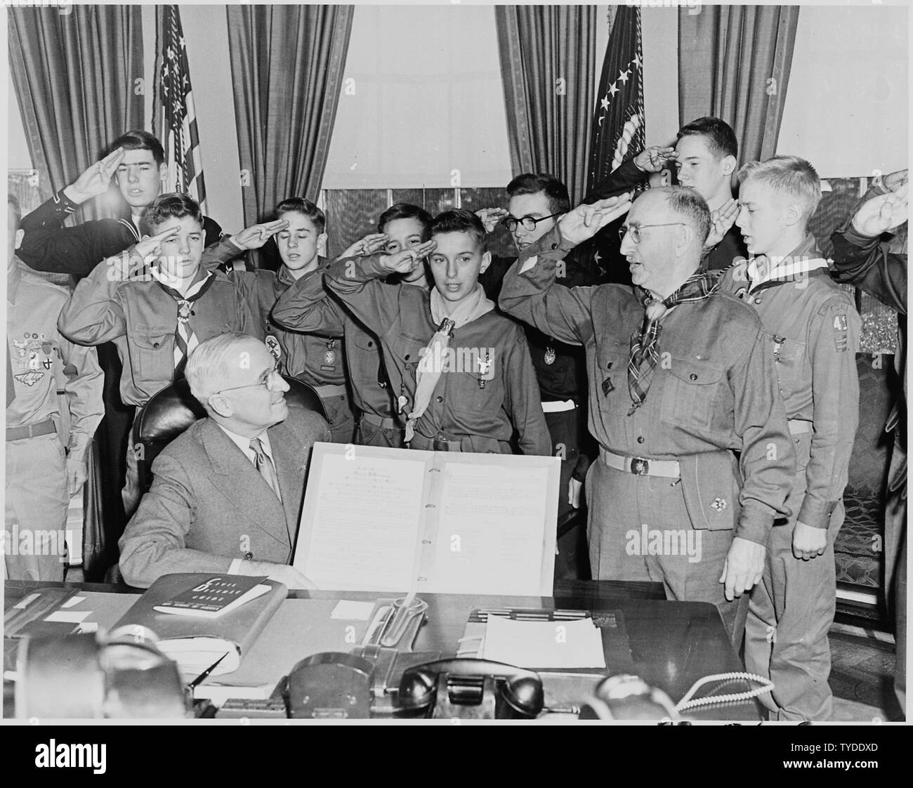 Photograph of President Truman in the Oval Office receiving a report on ...