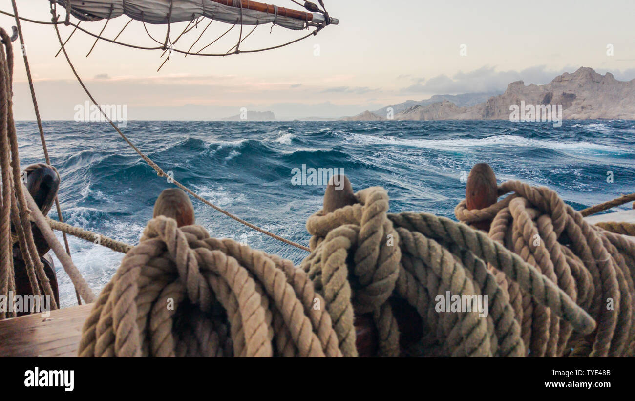 Old sailing ship running on the sea near the rocks. Belaying pin on ...