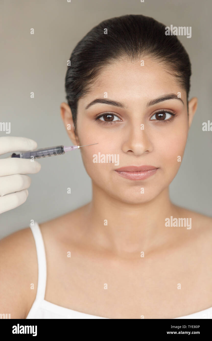 Indian young woman receiving botox injection in cheek Stock Photo - Alamy