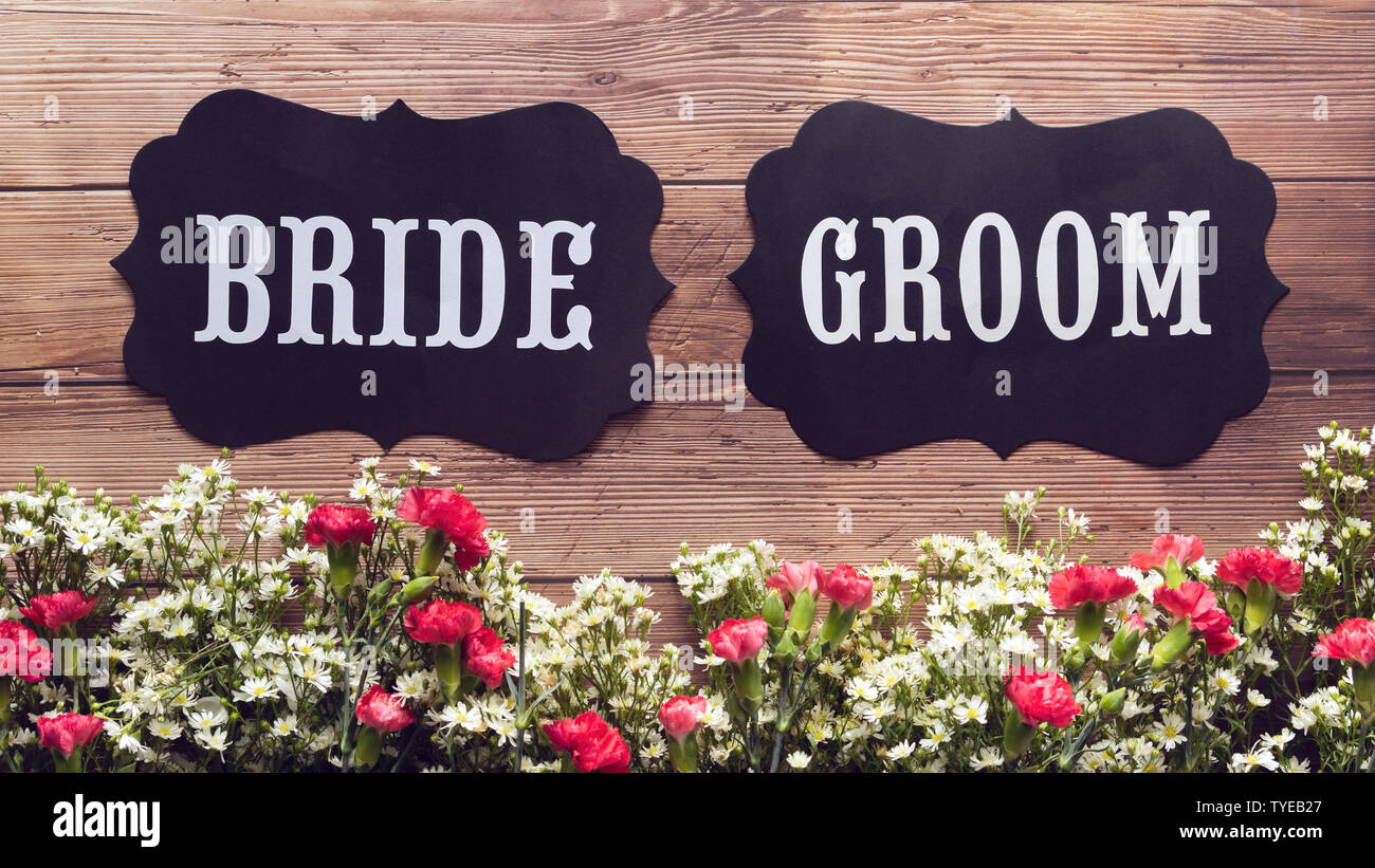 Bride and Groom text sign on wooden background decorated with flower ...
