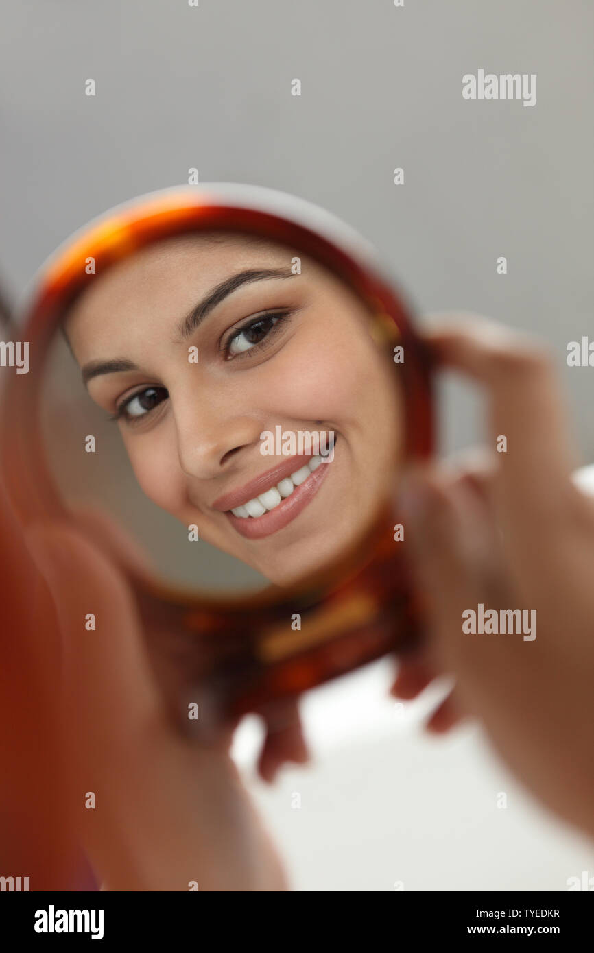 Indian young woman looking into a mirror Stock Photo - Alamy