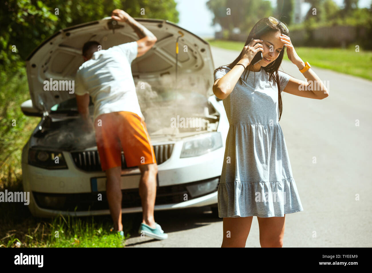 The young couple broke down the car while traveling on the way to rest ...