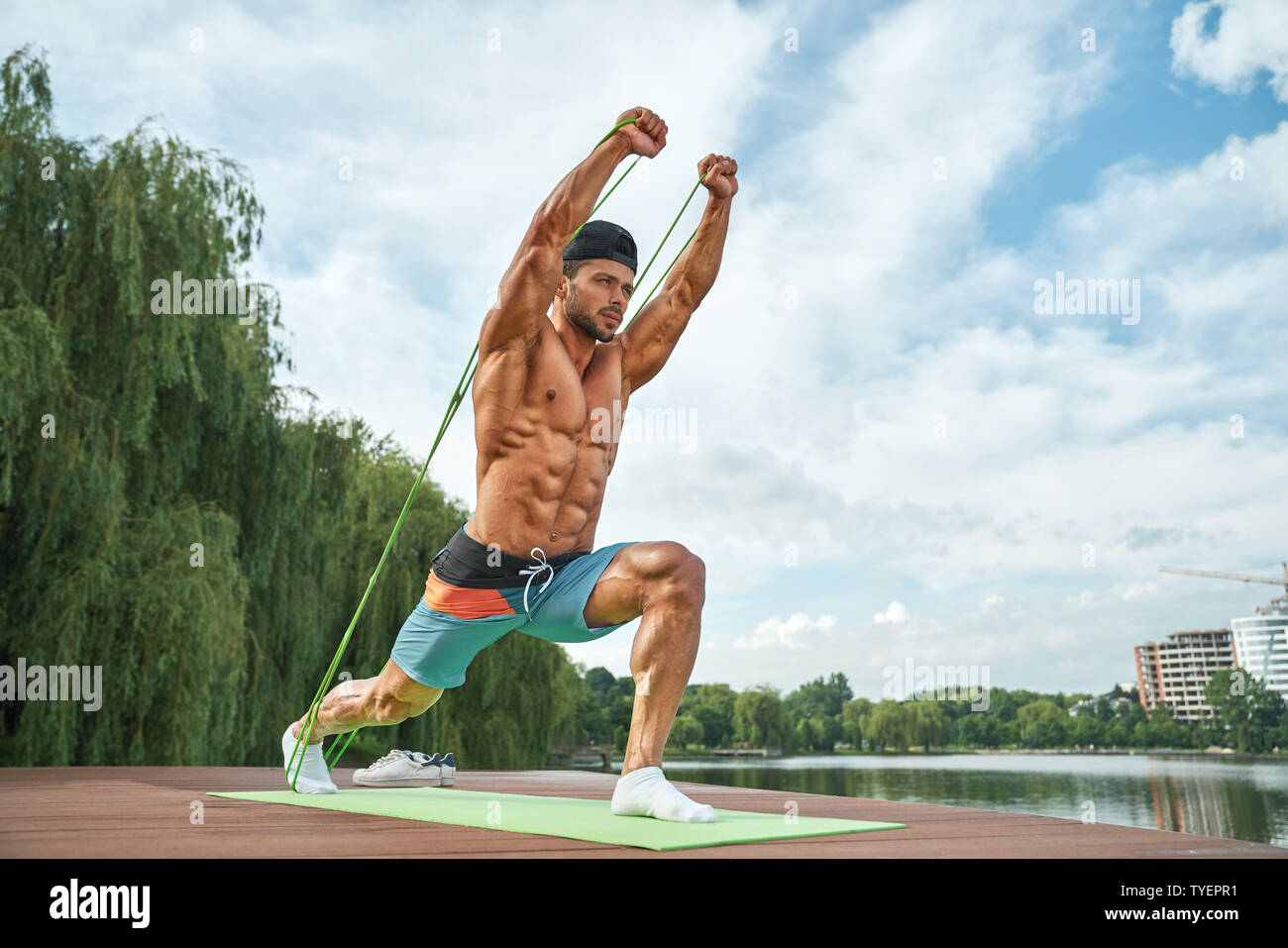 Front view of serious male stretching with silicons expander, pulling ...