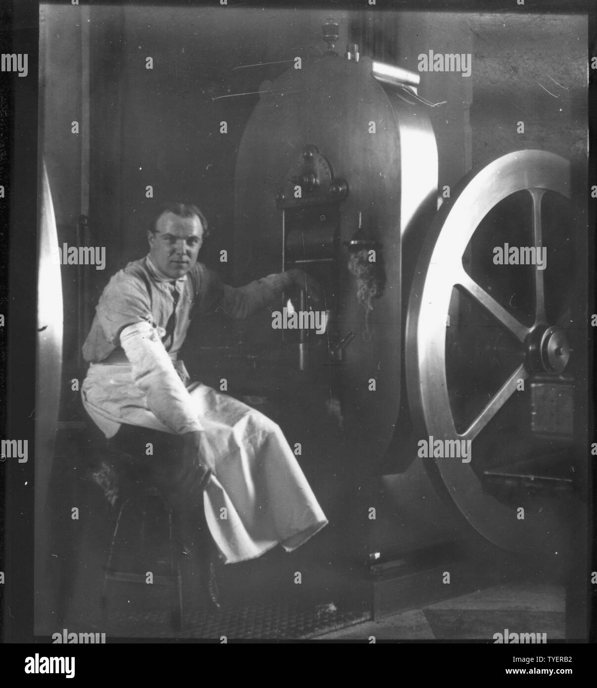 Photograph of a press operator sitting next to a coin press Stock Photo ...