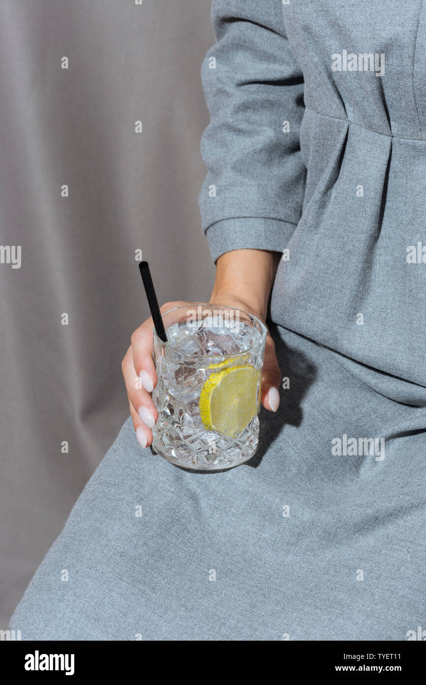 Woman helding gin tonic, grey and moody background Stock Photo - Alamy
