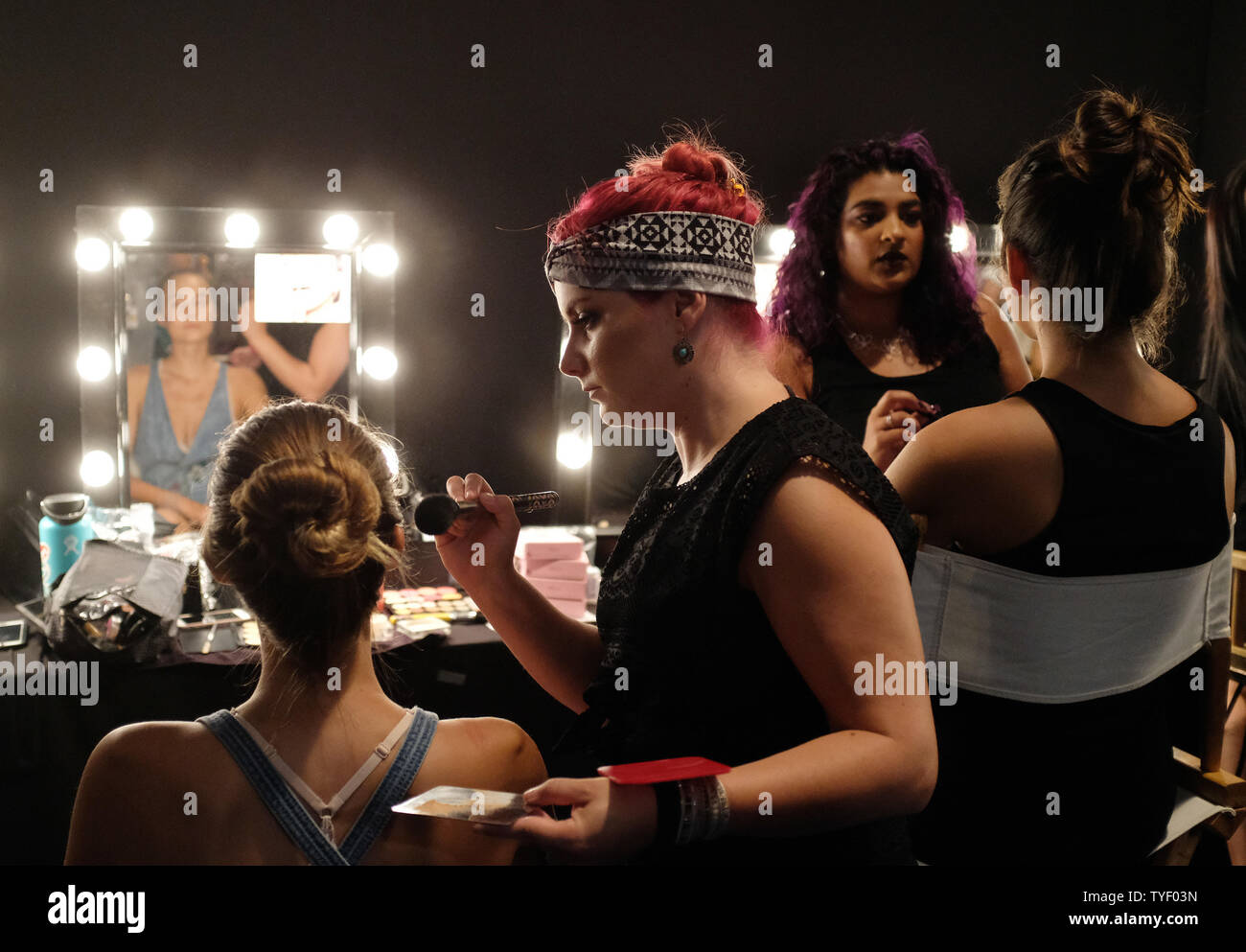 A runway model has makeup and hair done backstage during the Funkshion ...