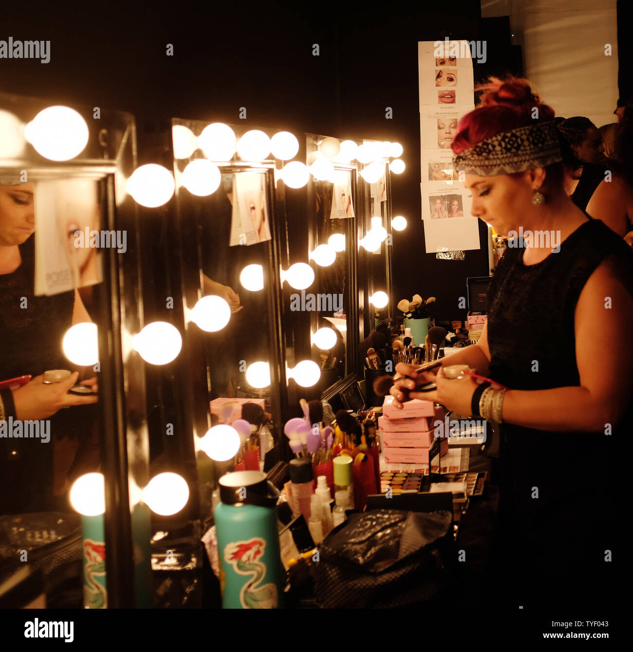 A runway model has makeup and hair done backstage during the Funkshion ...