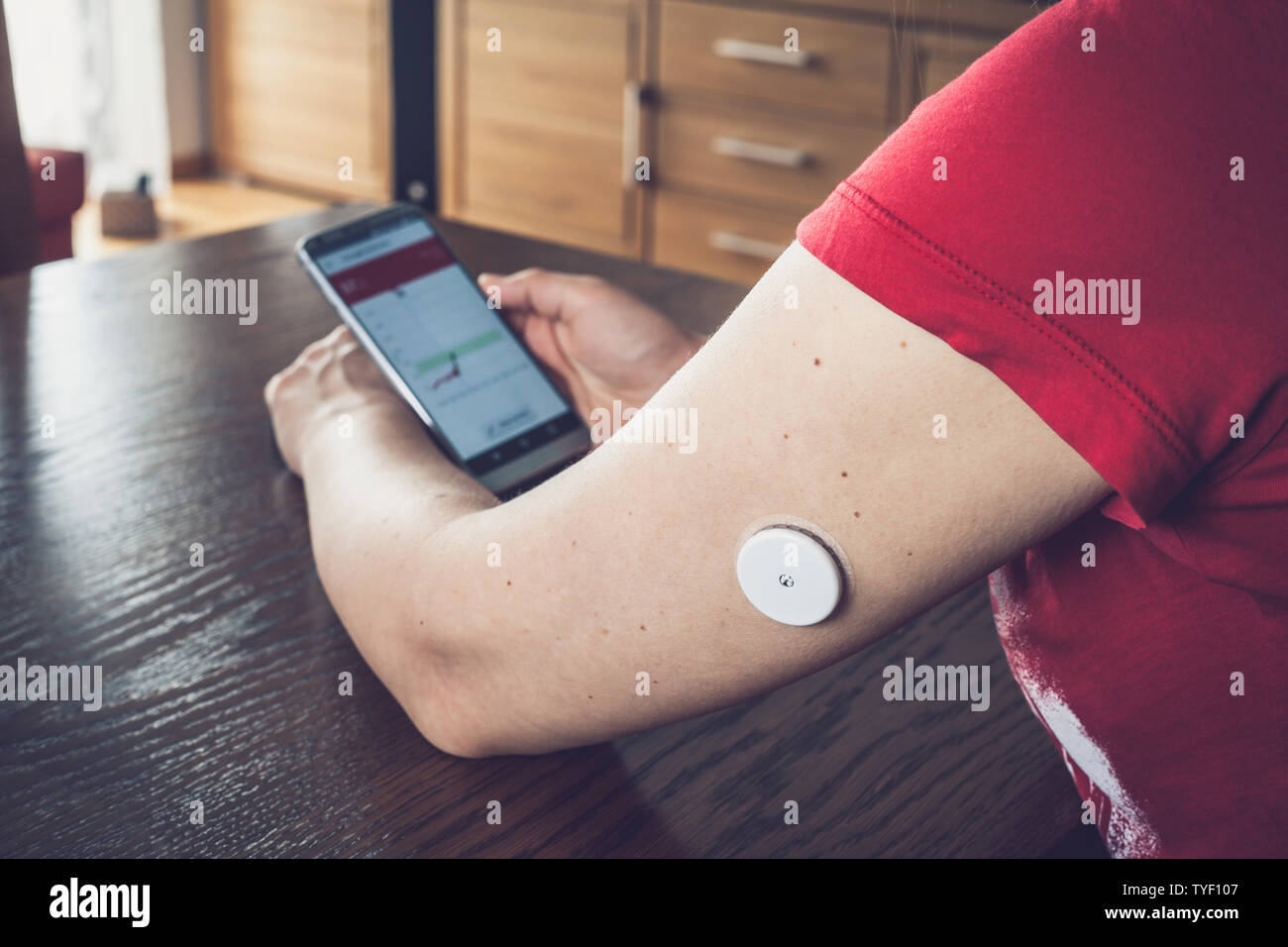 Woman checking glucose level with a remote sensor and mobile phone, new ...