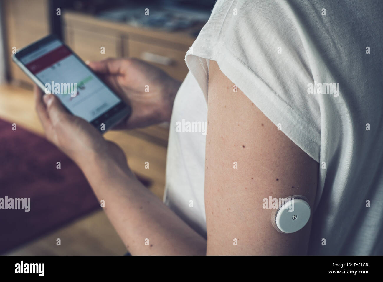 Woman checking glucose level with a remote sensor and mobile phone, new ...