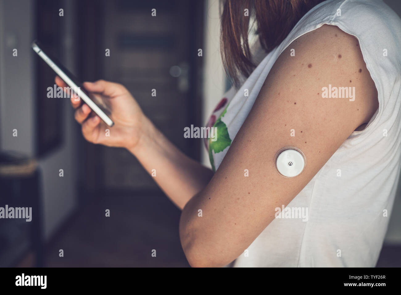 Woman checking glucose level with a remote sensor and mobile phone, new ...