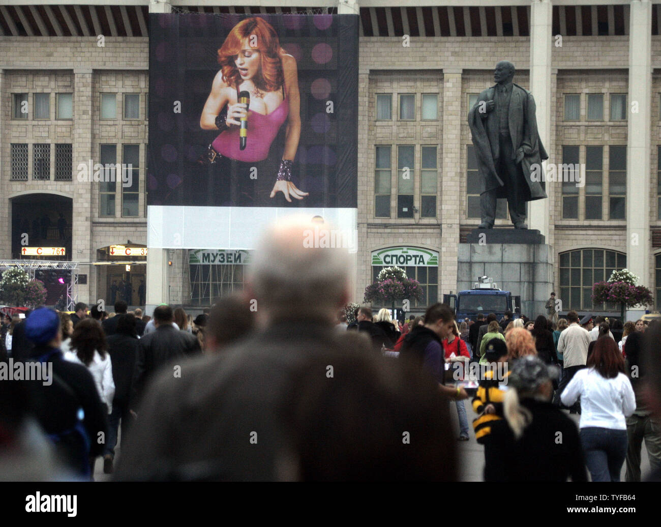 People pass near an advertisement of a concert of Madonna (L) and a ...