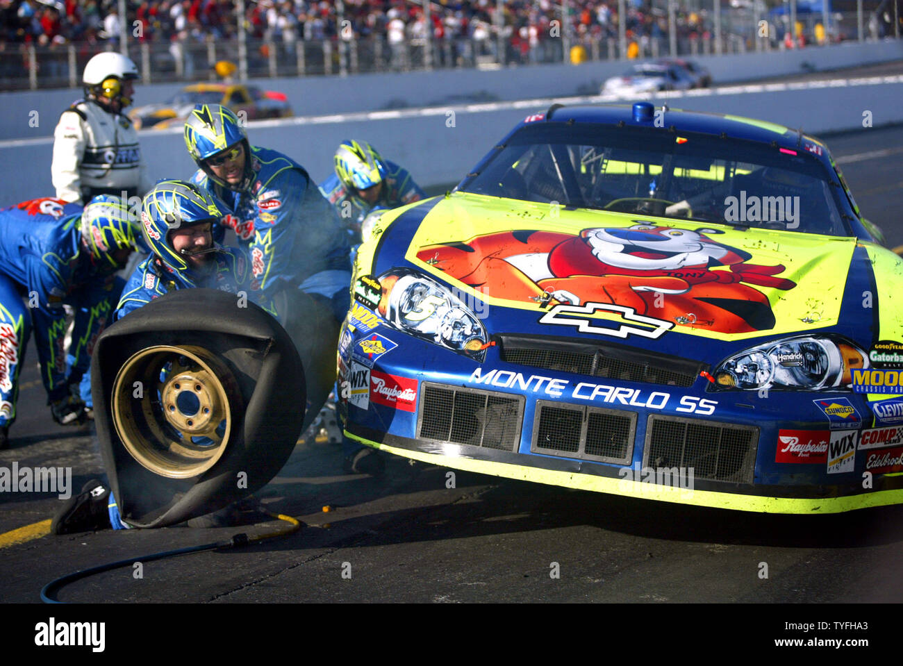 Kyle Busch's pit crew work on removing a blown tire during a pit stop ...