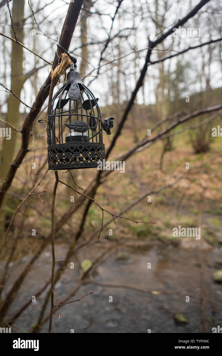 A black ornamental bird cage hangs from a branch as an offering, Dunino ...