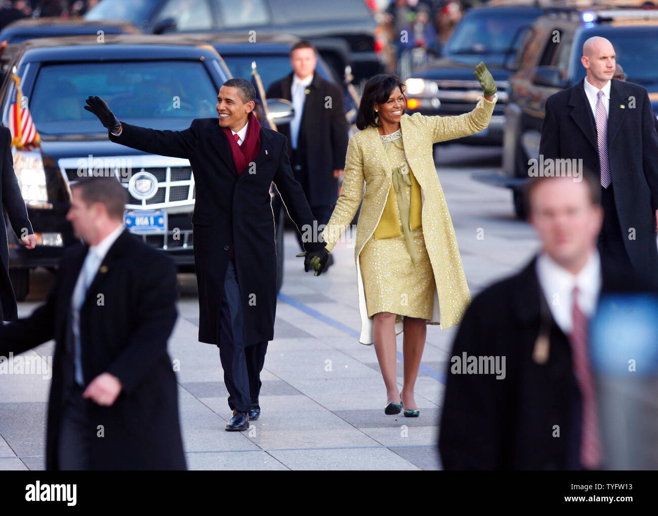 Barack Obama and Michelle Obama wave while walking the parade route ...