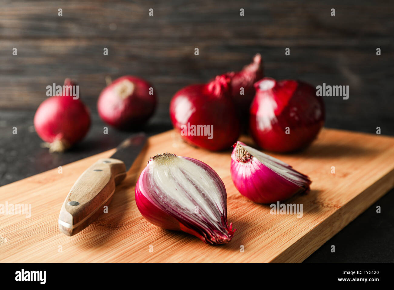 Composition with red onion, cutting board and knife on wooden table ...