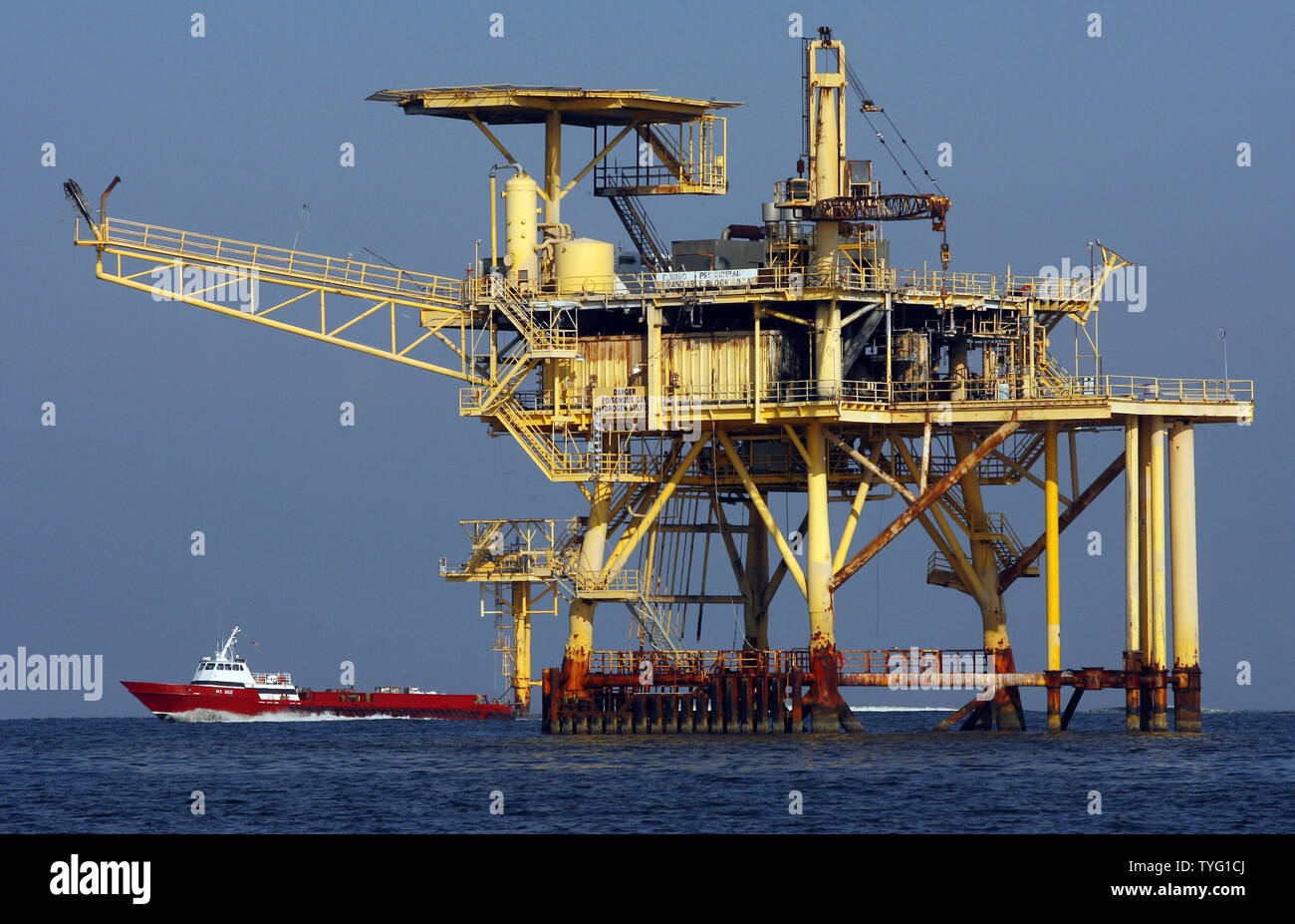 A supply boat, lower left, passes an oil production platform in the ...
