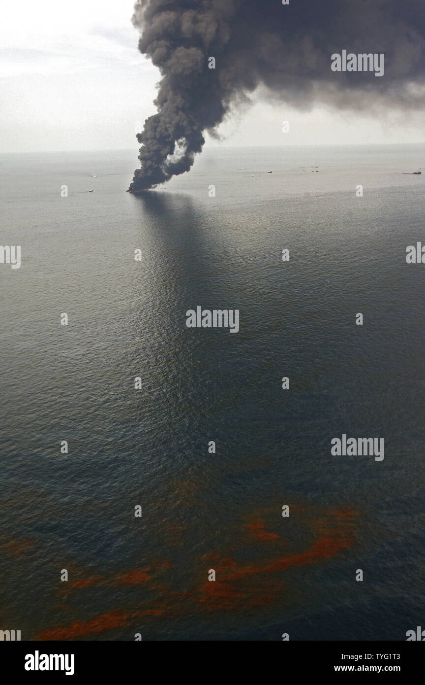 As crude oil pools on the surface of the water in the foreground, oil ...