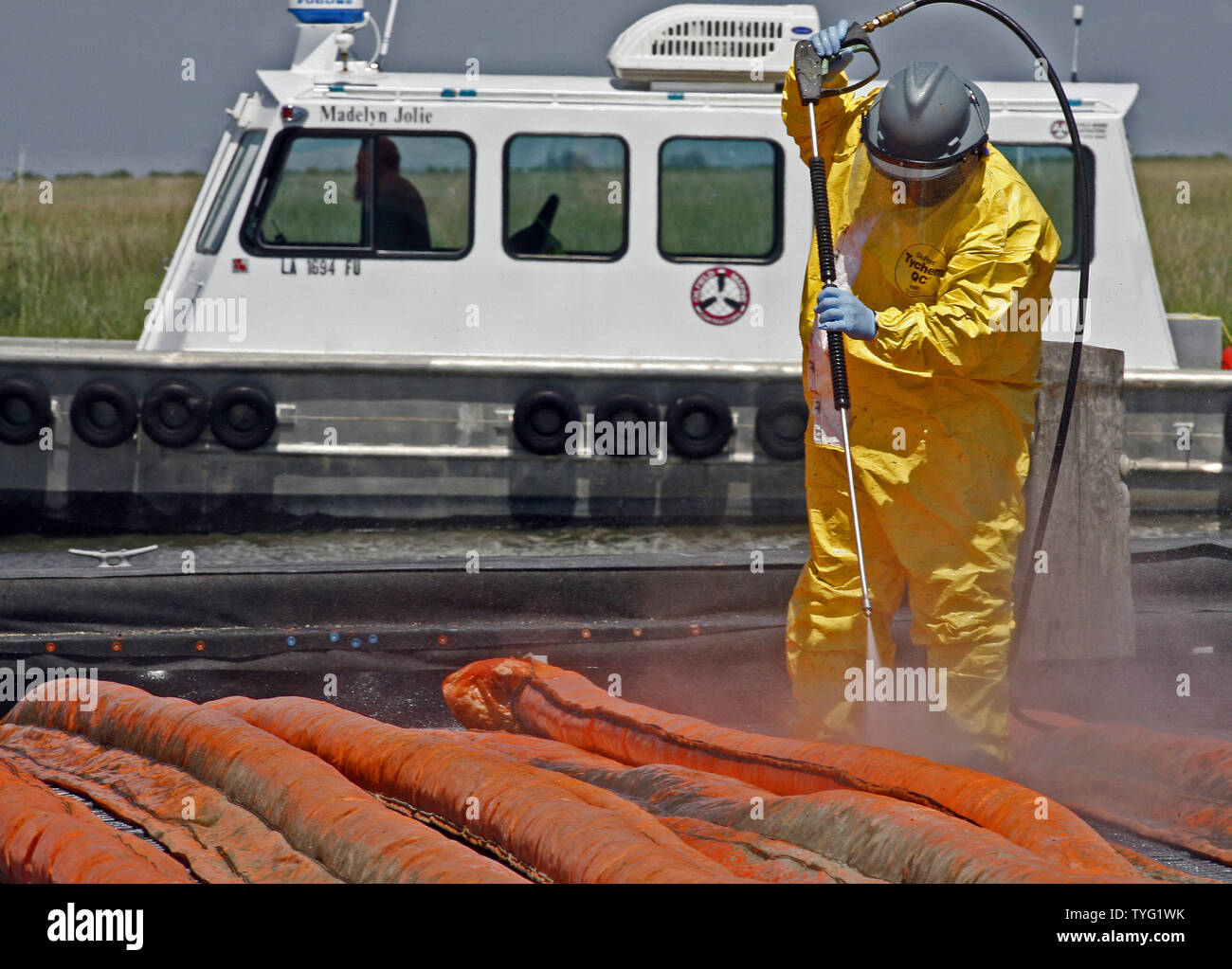 An unidentified BP worker pressure-washes oil containment booms that ...