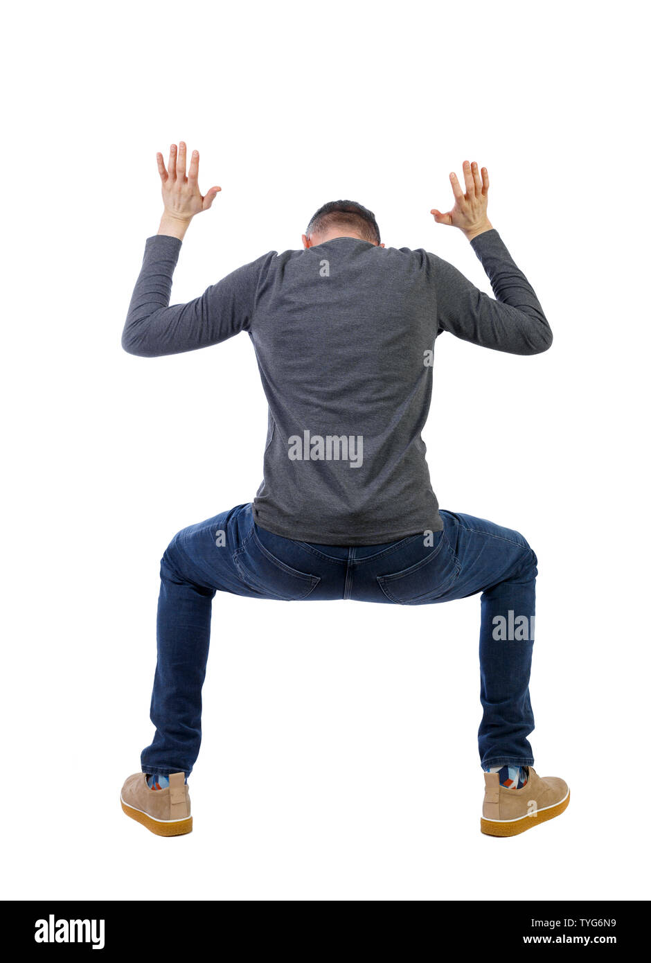 back view. man protects hands from what is falling from above. A young ...