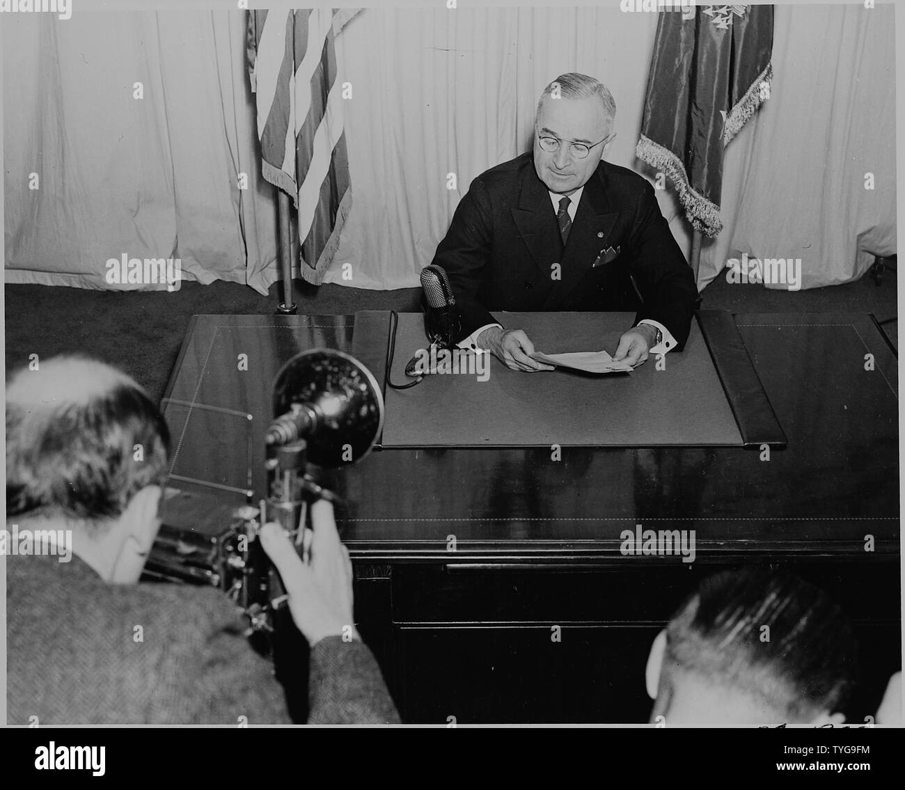 President Harry S. Truman seated at a desk, before a microphone ...