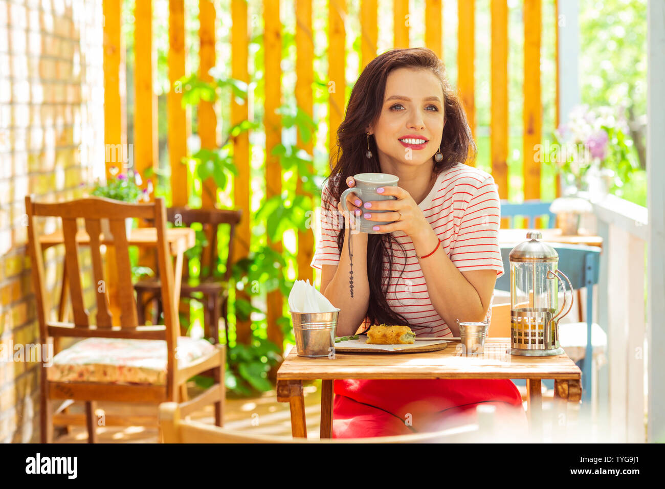 Smiling woman drinking coffee on a terrace of a cafe Stock Photo - Alamy