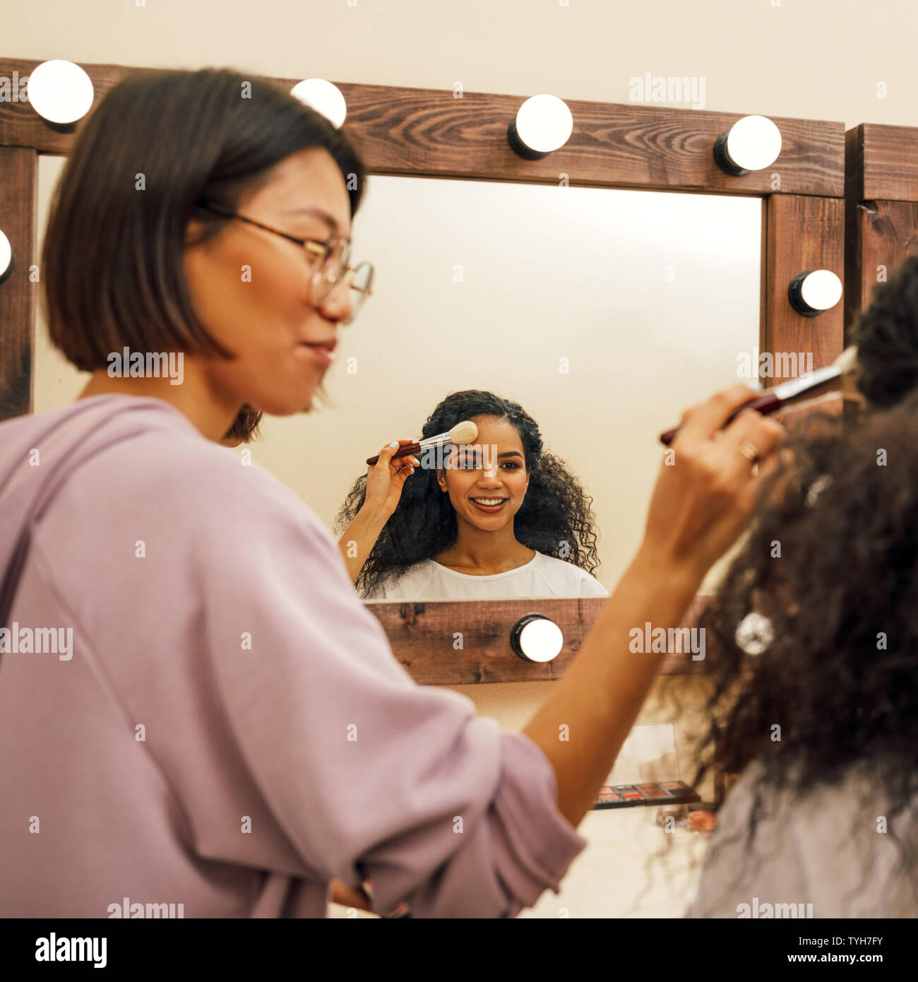 Make up artist and model preparing for photoshoot in dressing room ...