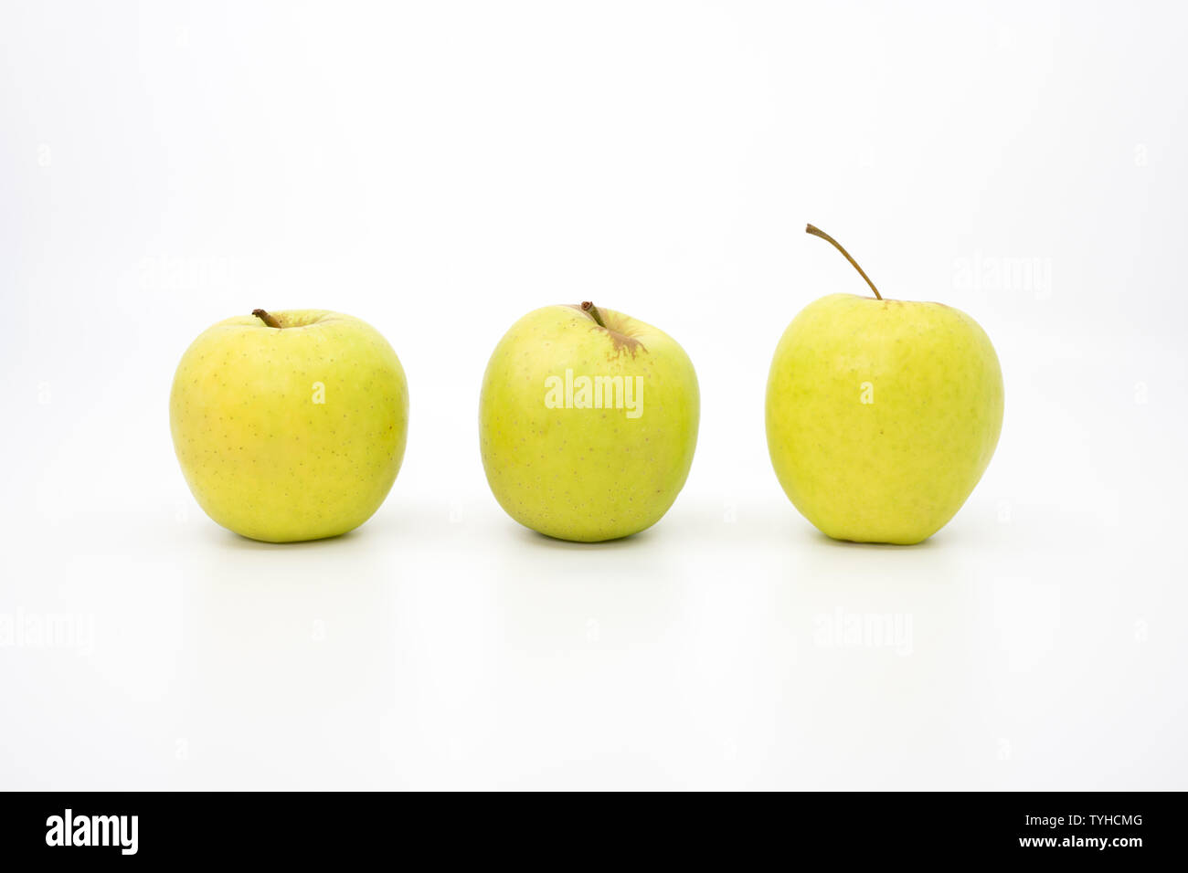 Three green apples in a row on a white background Stock Photo - Alamy