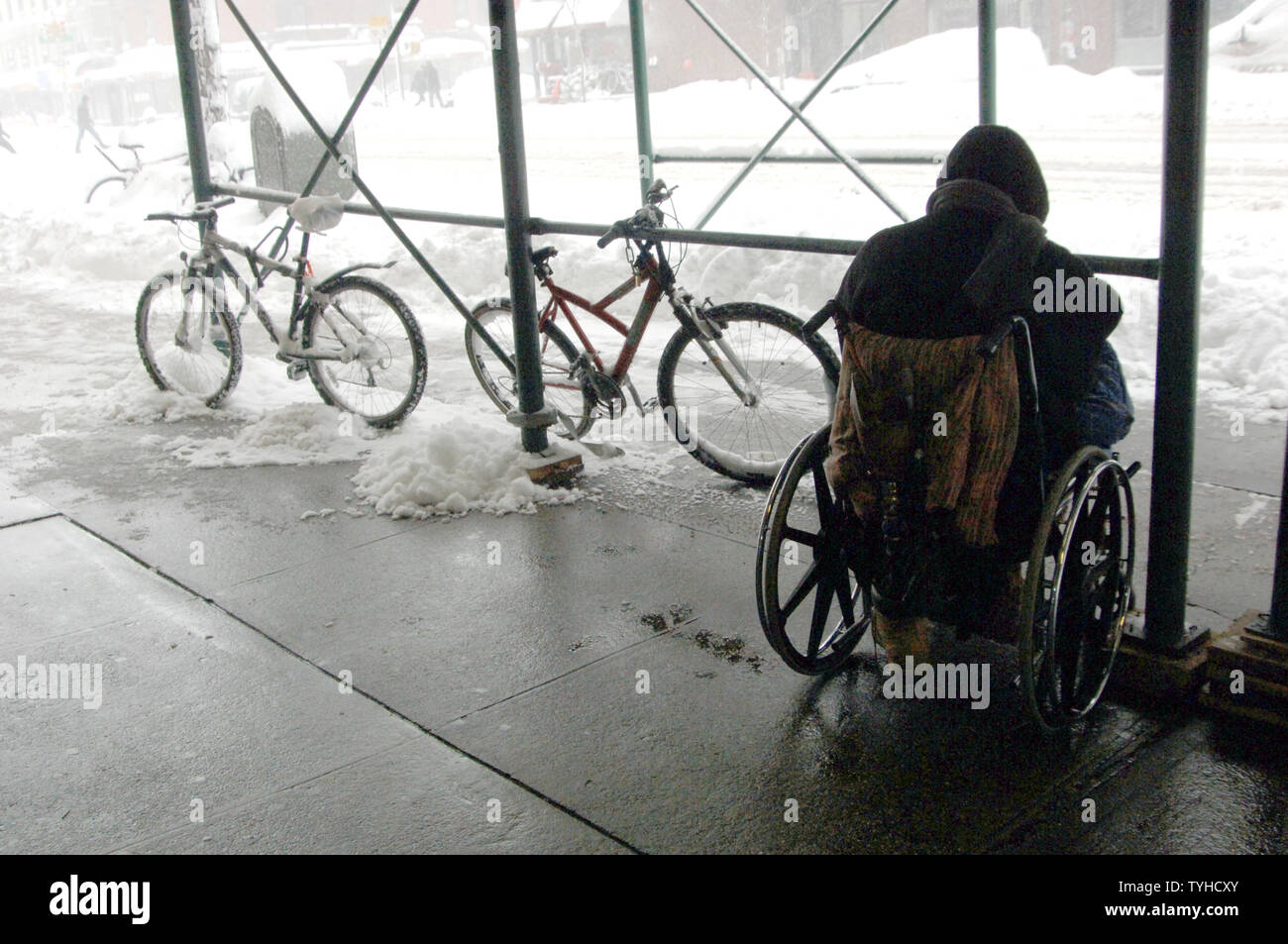 Homeless man watches the snow from his wheelchair under scaffolding in ...