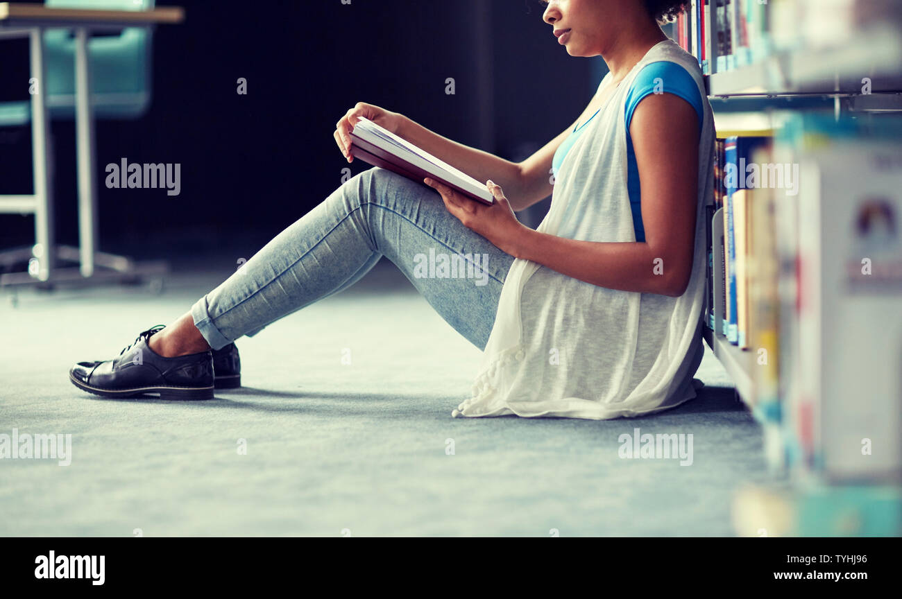 happy african student girl reading book at library Stock Photo - Alamy