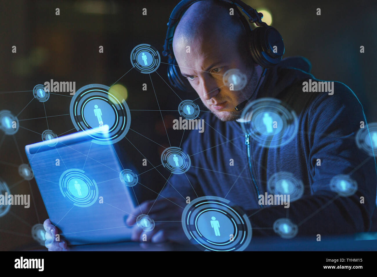 hacker in headset typing on laptop in dark room Stock Photo - Alamy