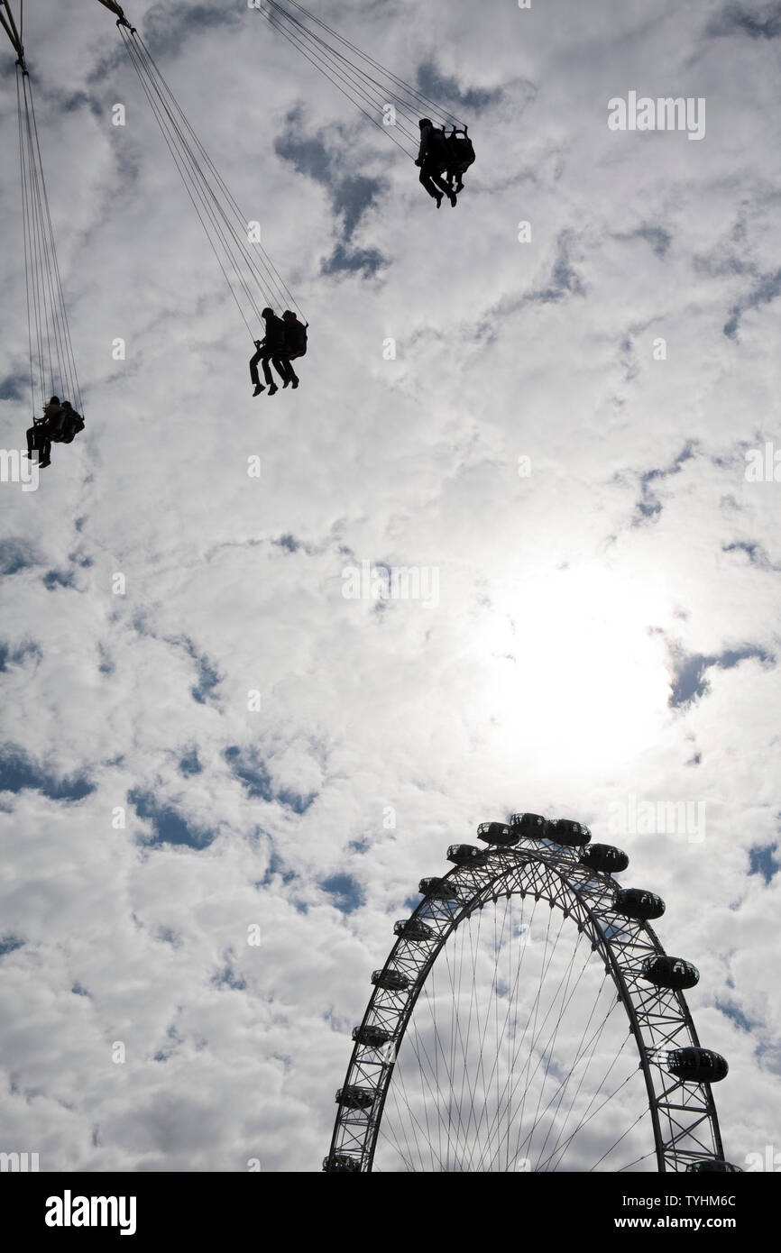 Passengers on a swing ride or chair swing ride with the London Eye in ...