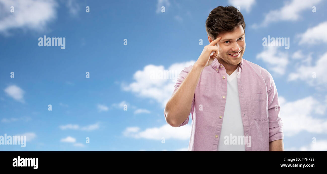 smiling young man pointing finger to his head Stock Photo - Alamy