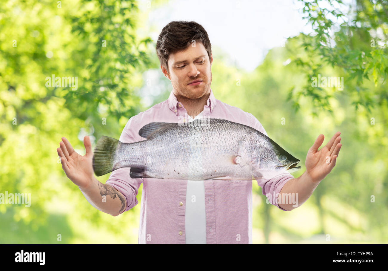 displeased young man showing size of fish Stock Photo - Alamy