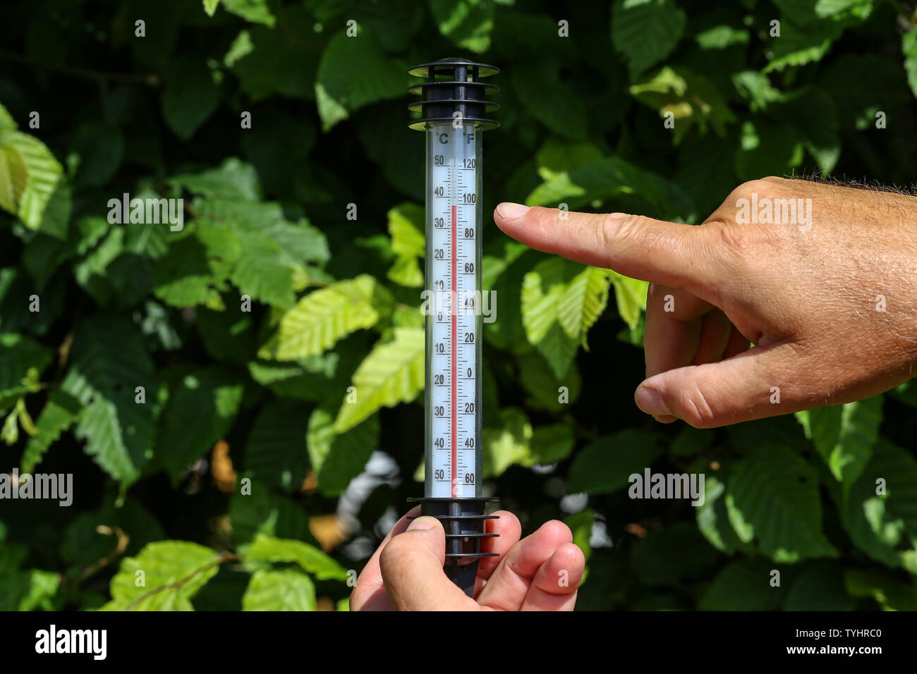 Hot Summer - Thermometer in hand, shows the heat Stock Photo - Alamy