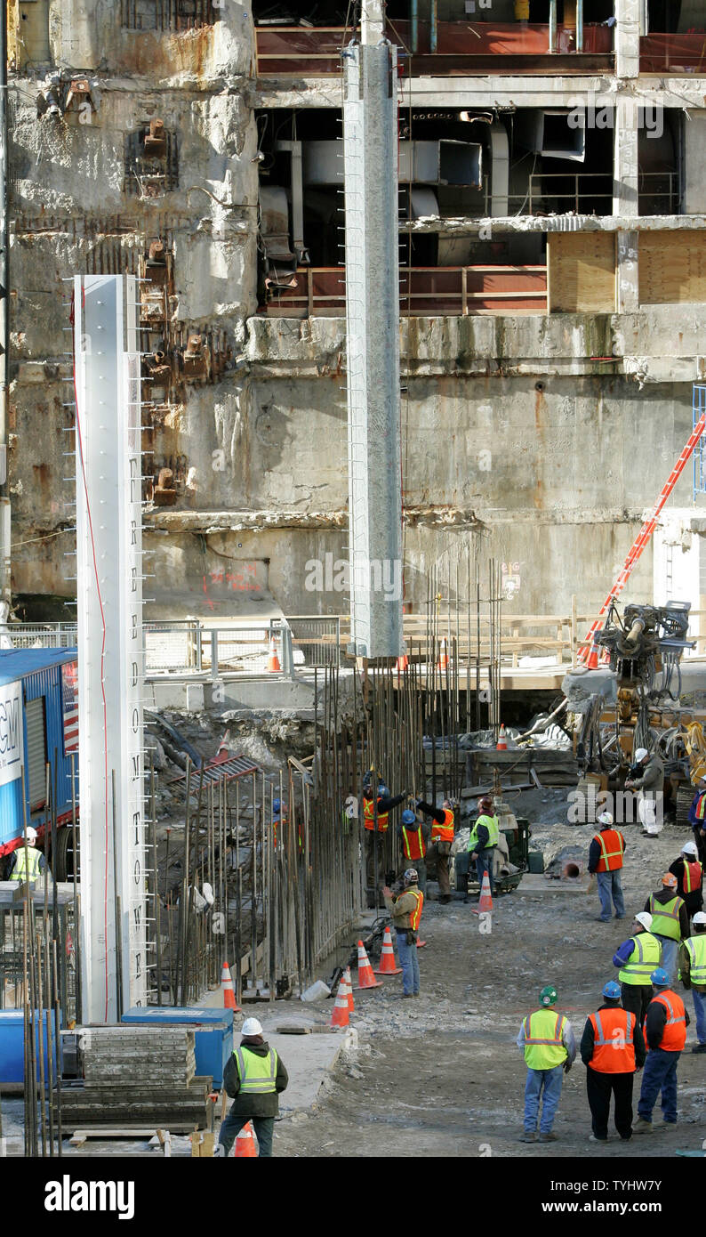 Construction workers guide a steel beam into place with the aid of a ...