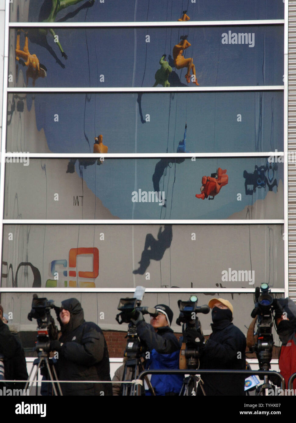 Aerial dancers are reflected in building windows while perform on the ...