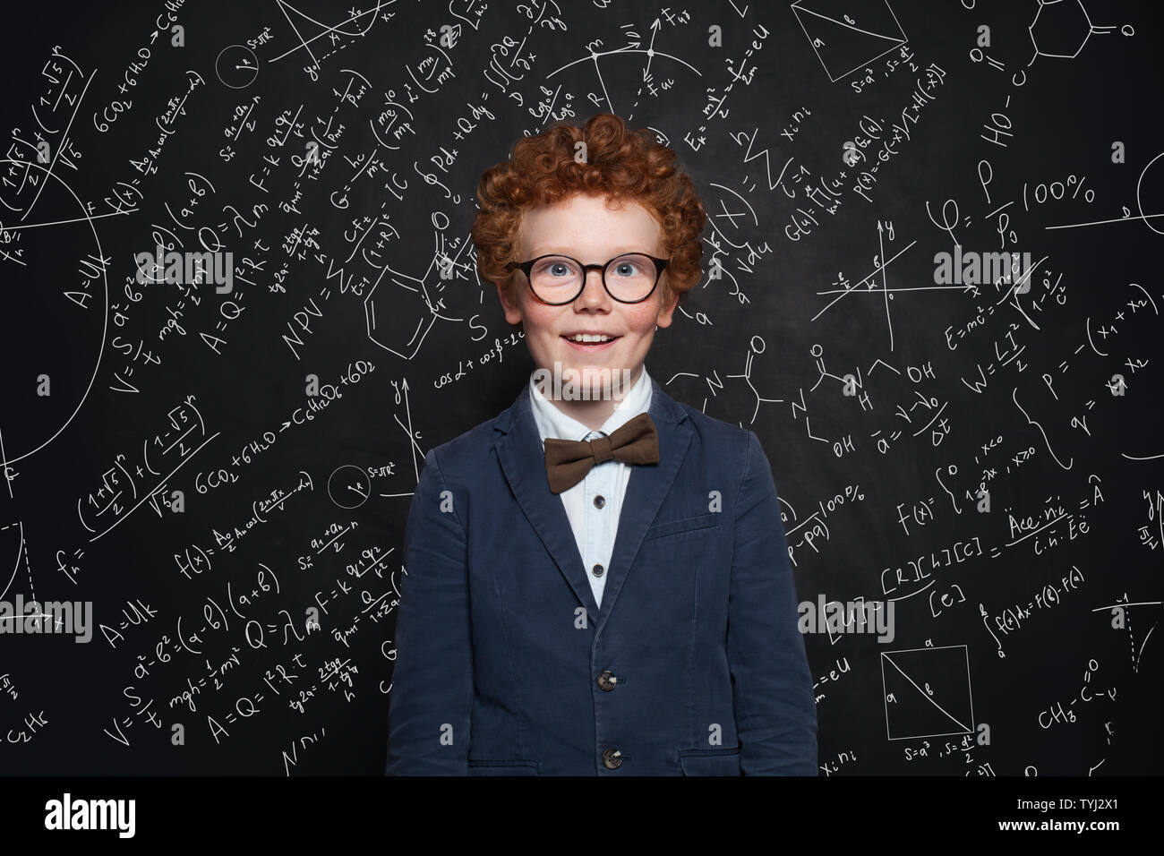 Happy smart kid in blue school suit on blackboard background with ...