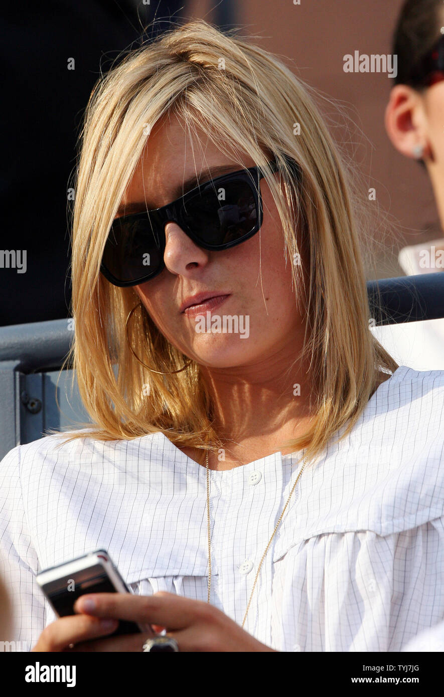 Maria Sharapova plays with her cell phone while Roger Federer plays ...