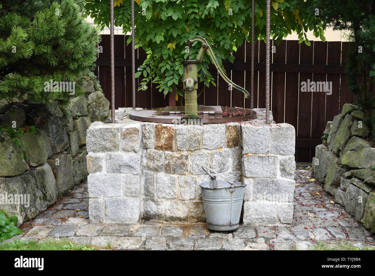 Stone well with water pump in the garden Stock Photo - Alamy