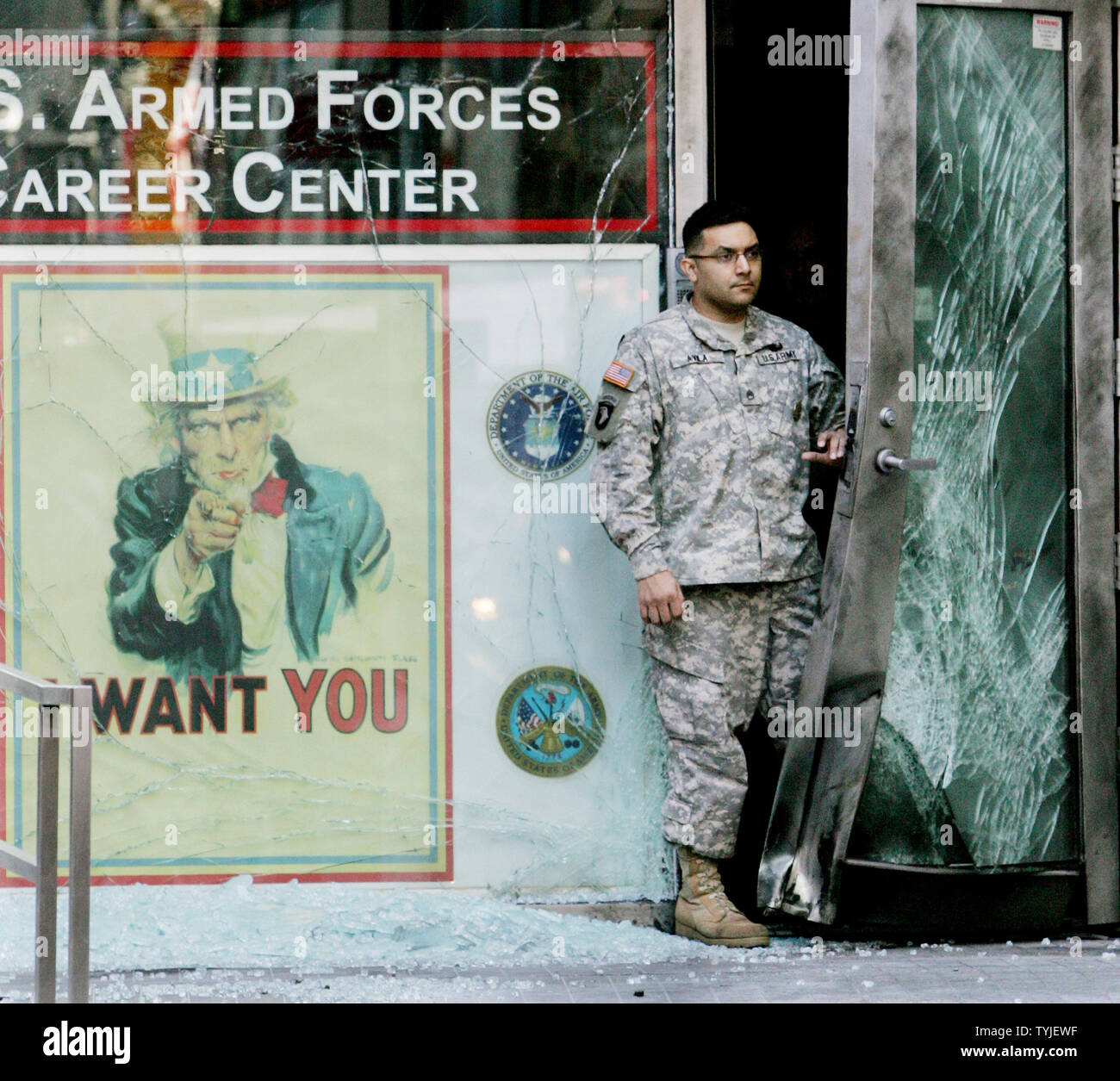 A military official stands behind the damaged door and a pile of ...