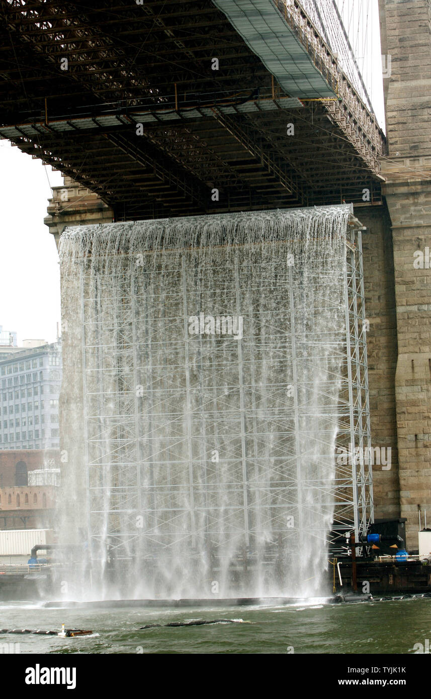 An 80-foot waterfall pours out from under the Brooklyn Bridge which is ...