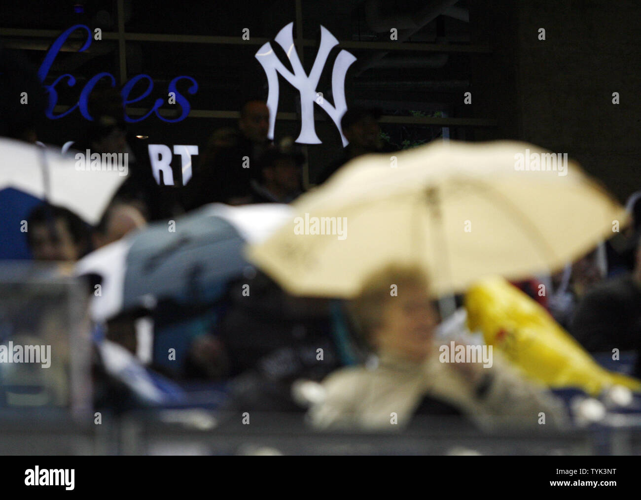 Fans sit in the rain during a rain delay preventing the start of a game ...