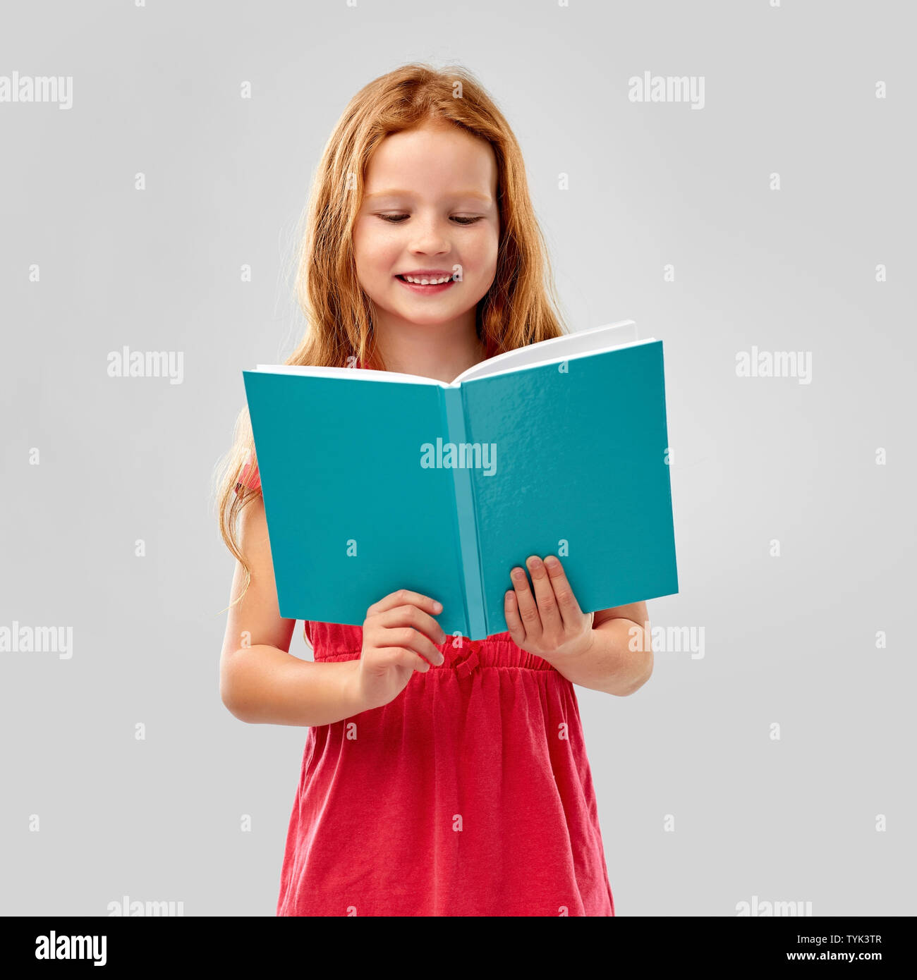 smiling red haired girl reading book Stock Photo - Alamy